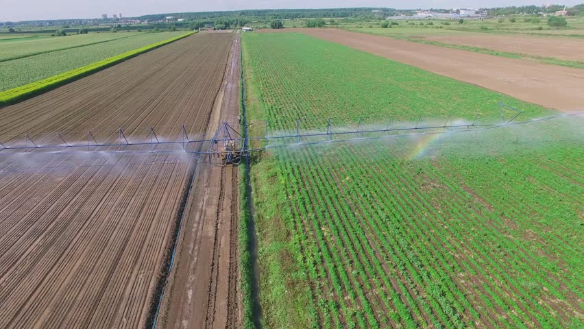 Tractor Moves Watering System Across Farm Field At Summer Sunny Day ...