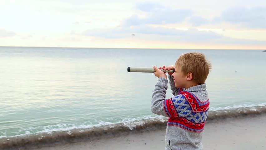 Funny Little Boy Looking Through Telescope At Camera At Sea Background ...
