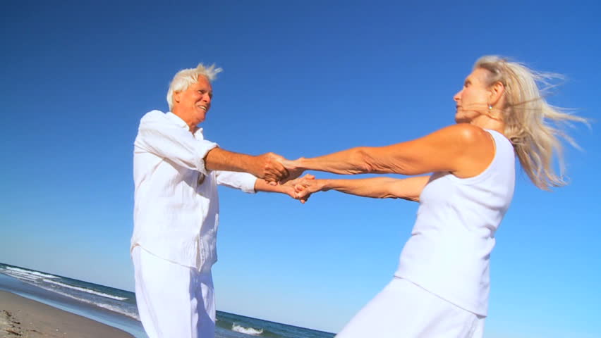 Attractive Senior Couple Dancing On The Beach And Confidently Enjoying A