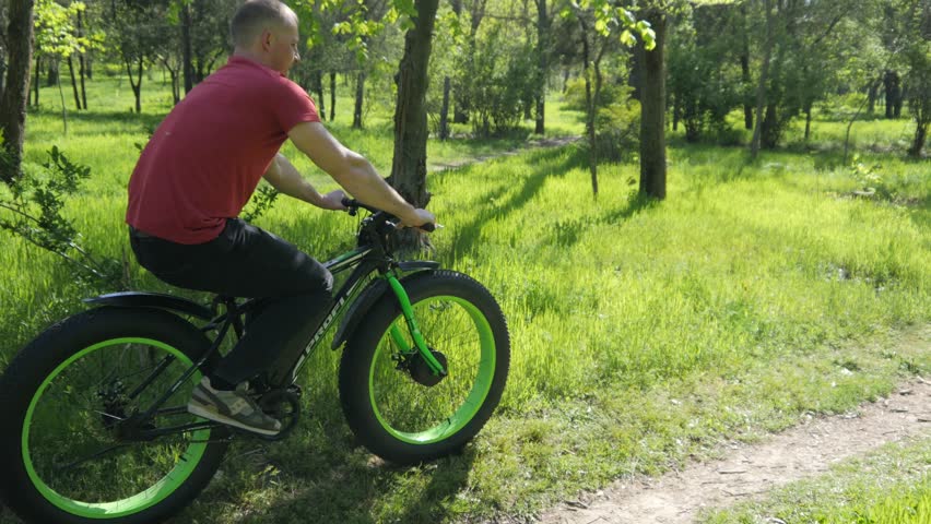 KHERSON, UKRAINE - APR 20, 2017: Man Riding Electric Bicycle In A Green ...