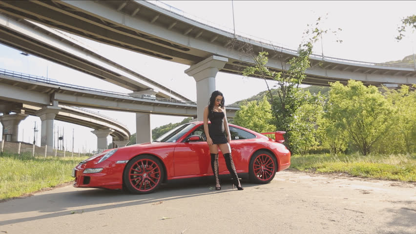 A Beautiful Slender Girl In A Black Tight Dress Posing Against A Red ...