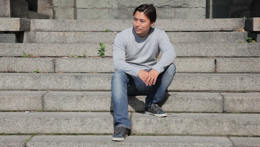 A Young Man In His 20s, Sitting Down Outside On A Set Steps. Wearing ...